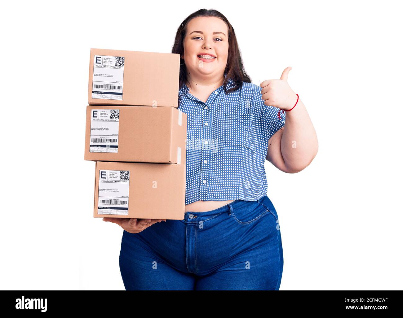 Young plus size woman holding delivery package smiling happy and ...