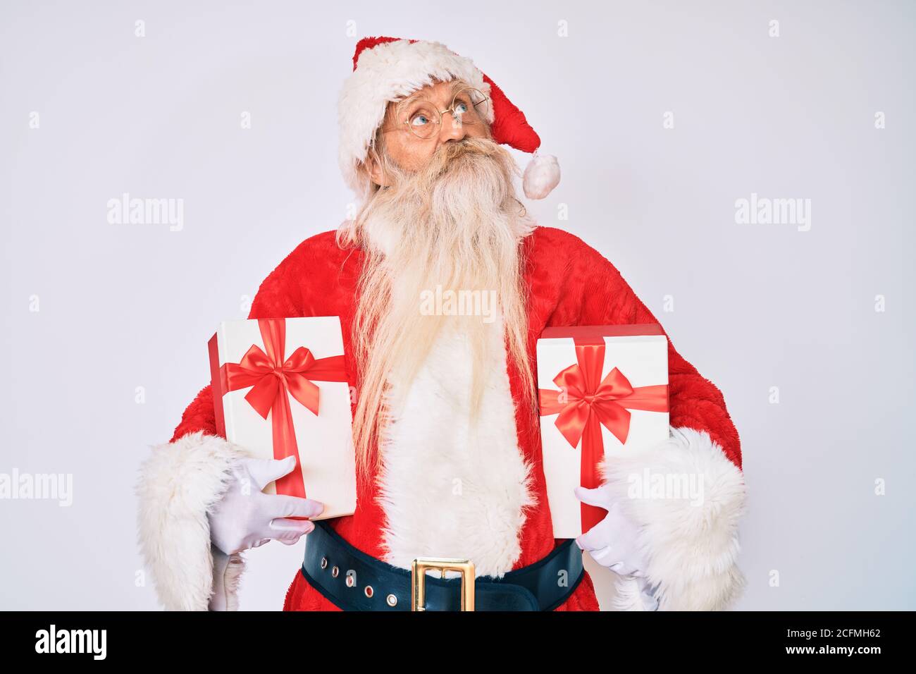 Old senior man wearing santa claus costume holding presents smiling ...