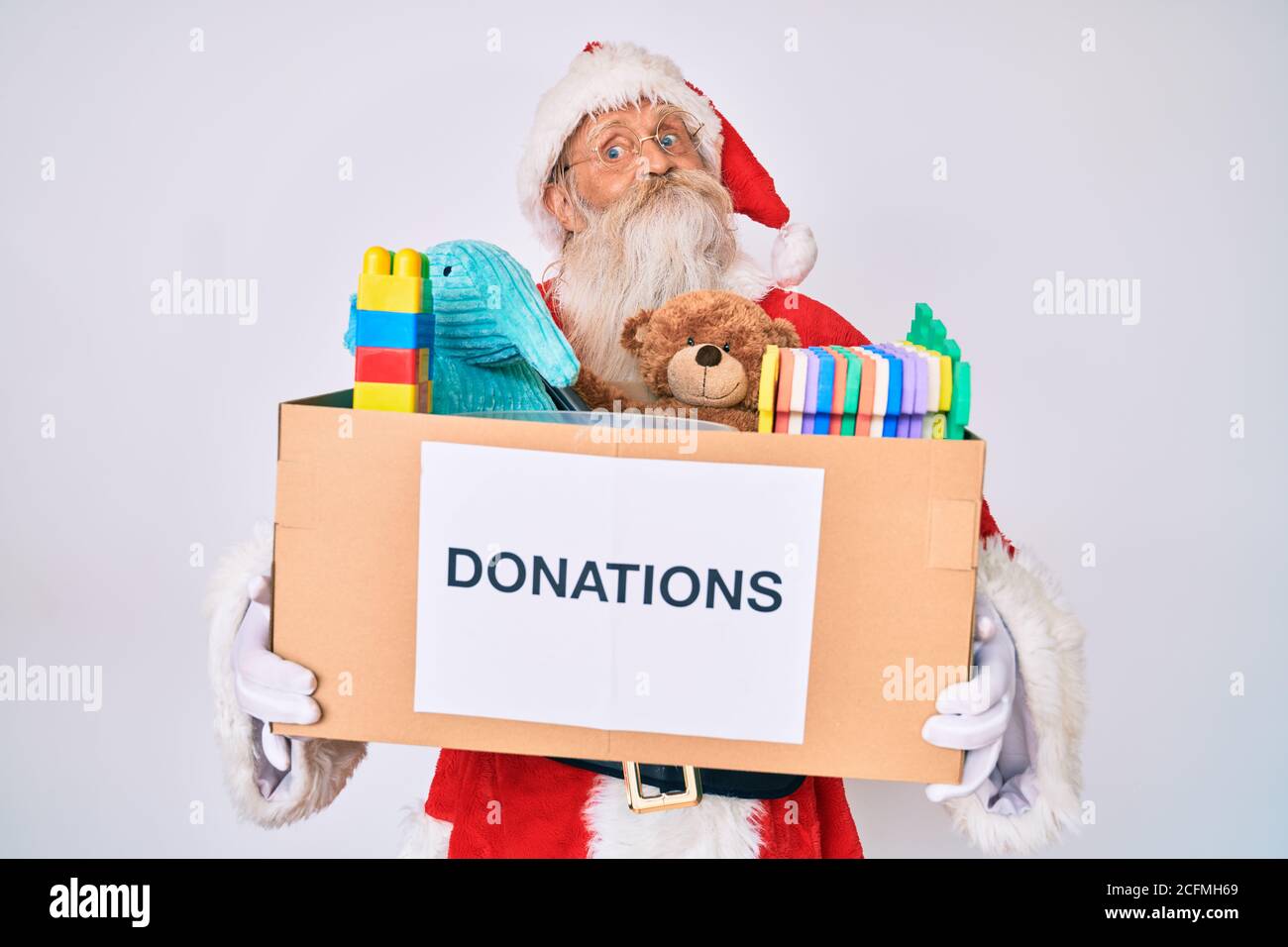 Old senior man wearing santa claus costume holding donation box smiling ...