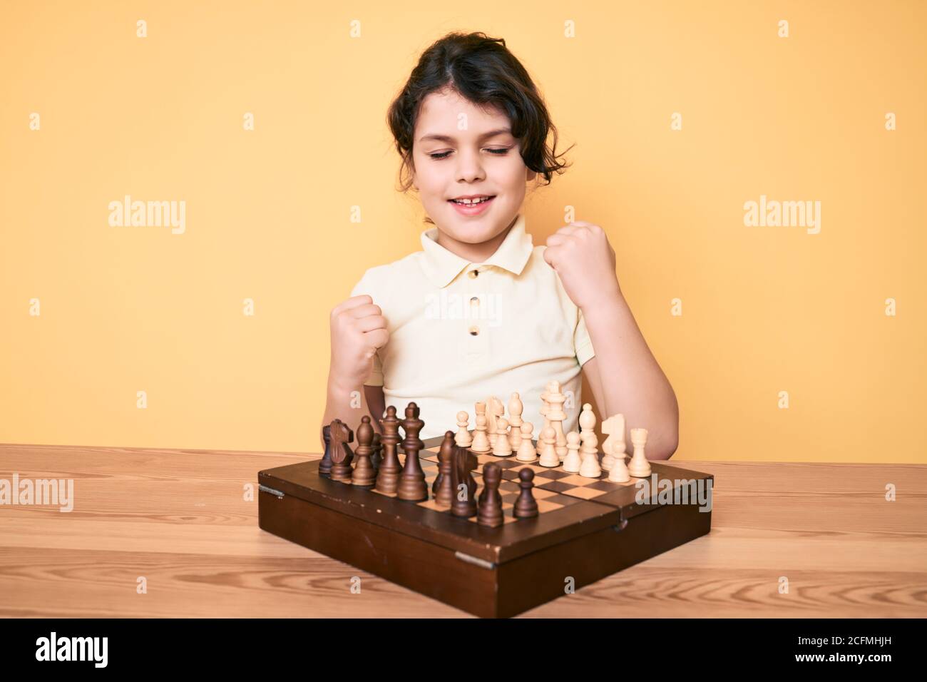 Cute hispanic child playing chess sitting on the table celebrating ...