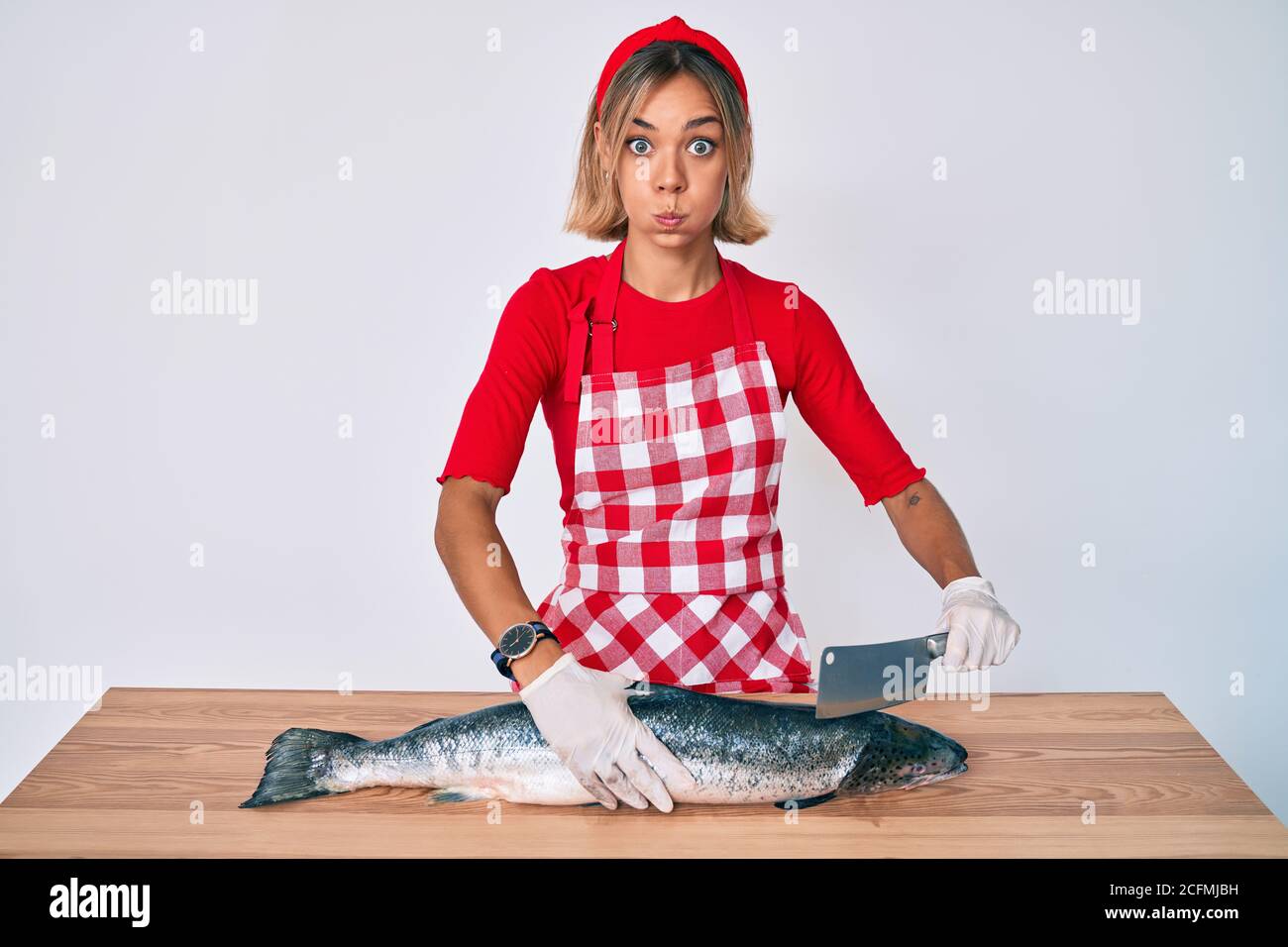 Beautiful caucasian woman fishmonger selling fresh raw salmon puffing ...
