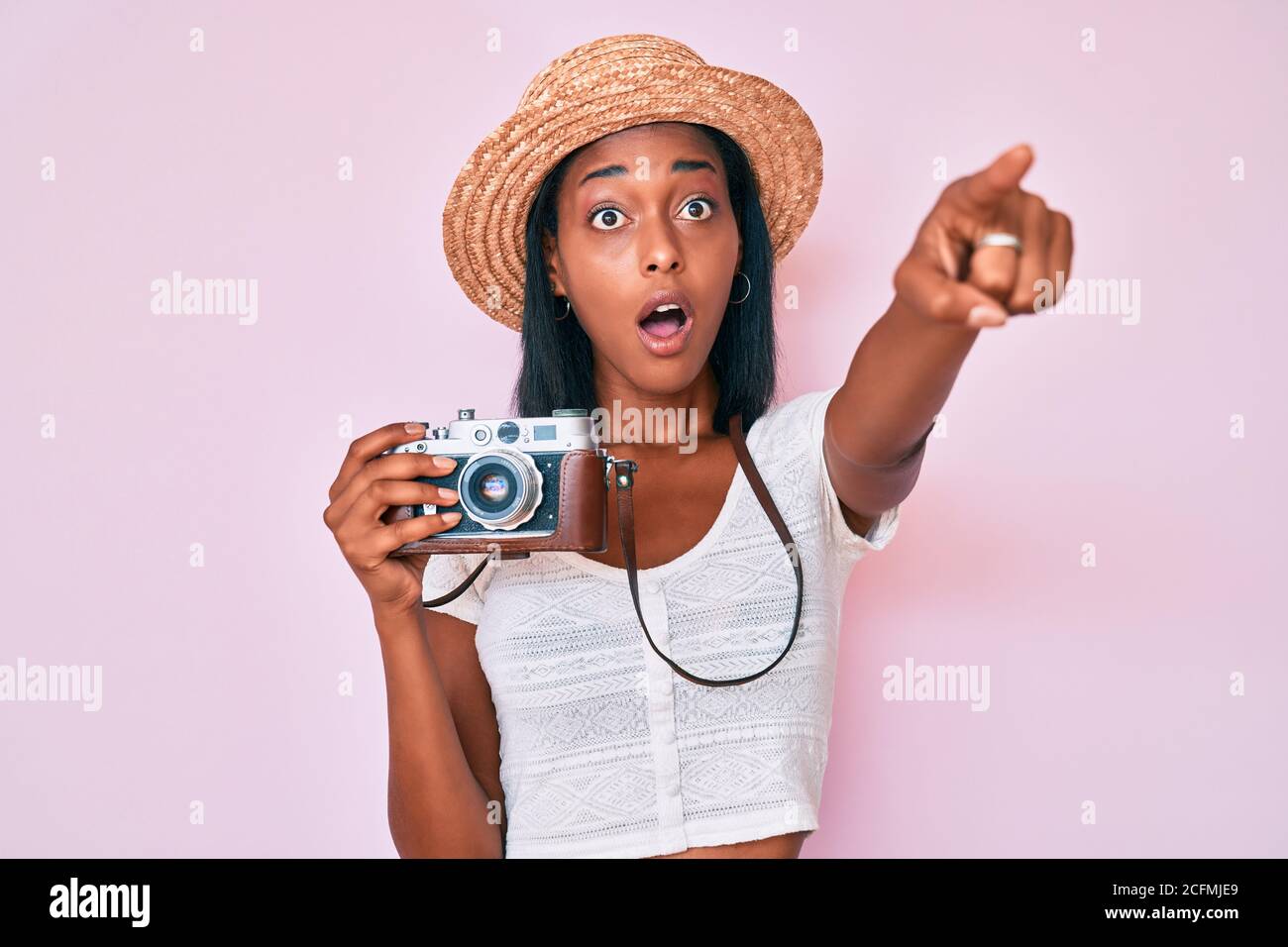 Young african american woman wearing summer hat holding vintage camera ...