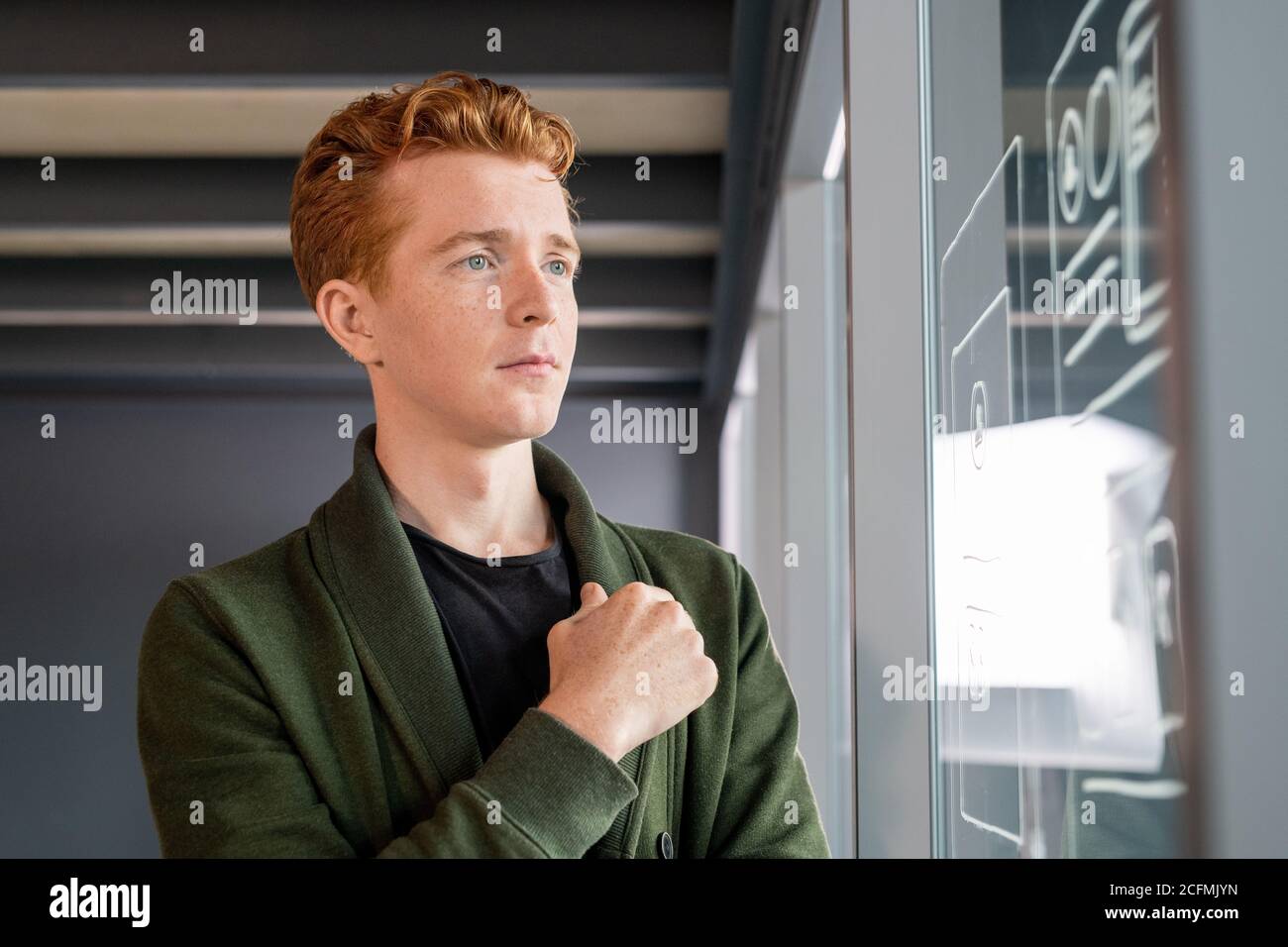 Young serious software developer standing in front of noticeboard with ...