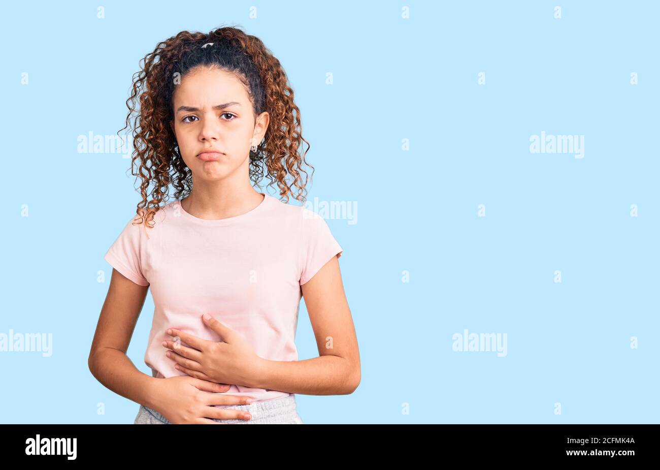 Beautiful kid girl with curly hair wearing casual clothes with hand on ...