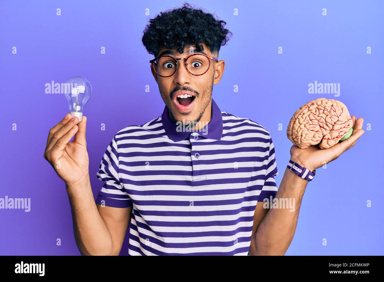 Young arab handsome man holding brain and lightbulb for inspiration and ...