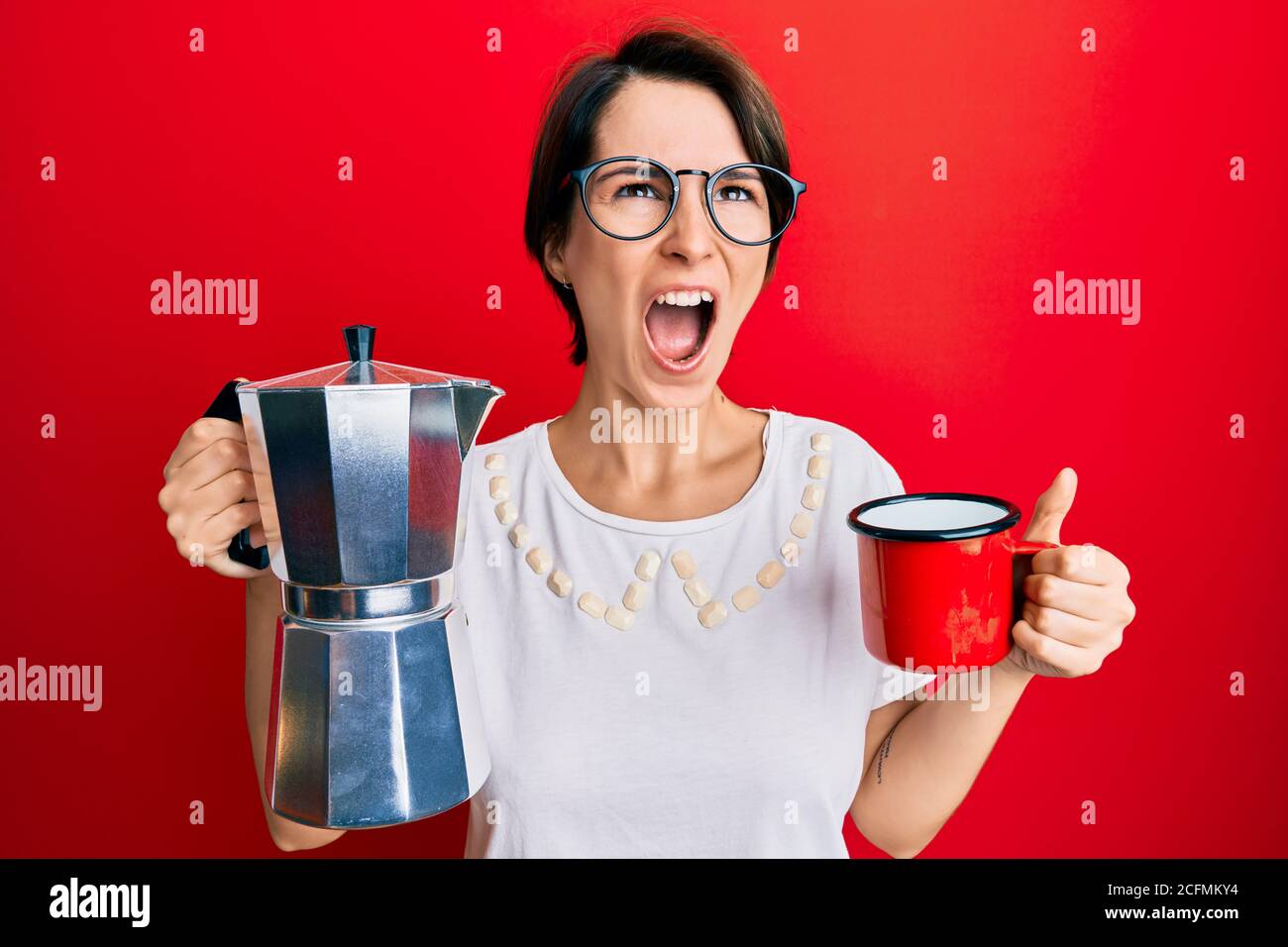 Young brunette woman with short hair drinking italian coffee angry and ...
