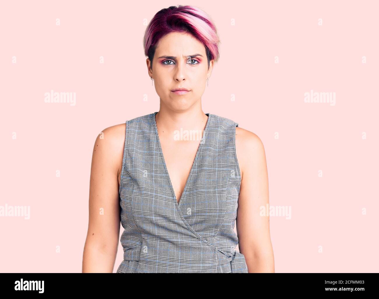 Young beautiful woman with pink hair wearing casual clothes skeptic and ...