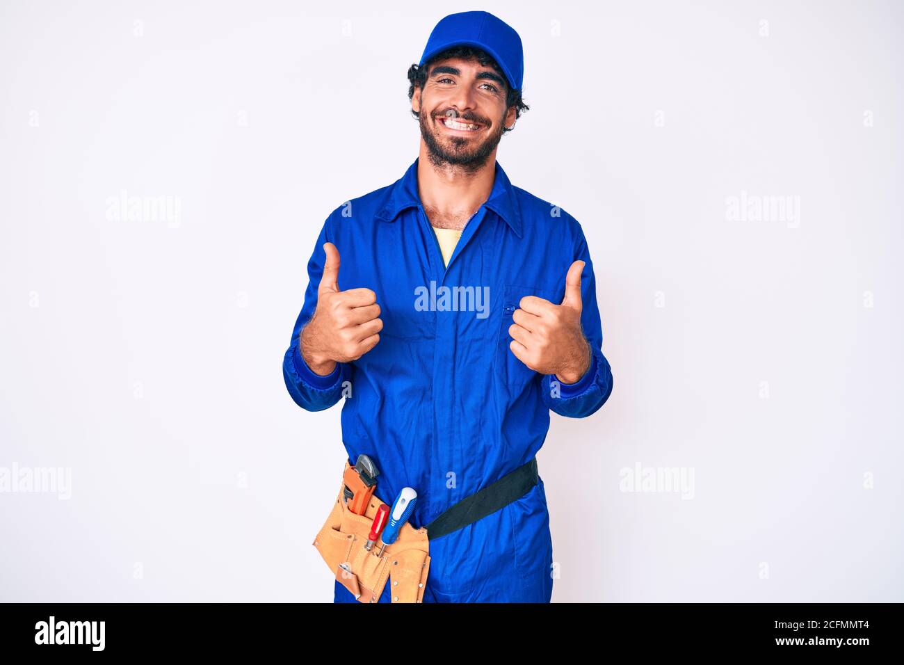 Handsome young man with curly hair and bear weaing handyman uniform ...