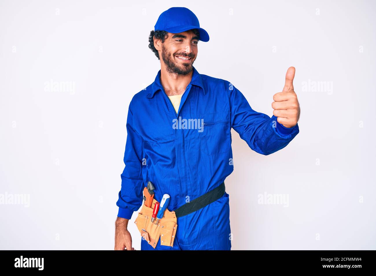 Handsome young man with curly hair and bear weaing handyman uniform ...