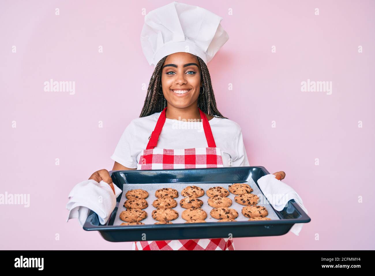 Young african american woman with braids wearing baker uniform holding ...