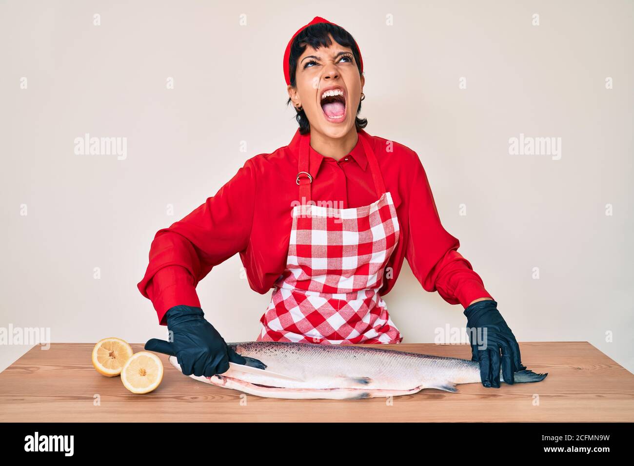 Beautiful brunettte woman fishmonger selling fresh raw salmon angry and ...