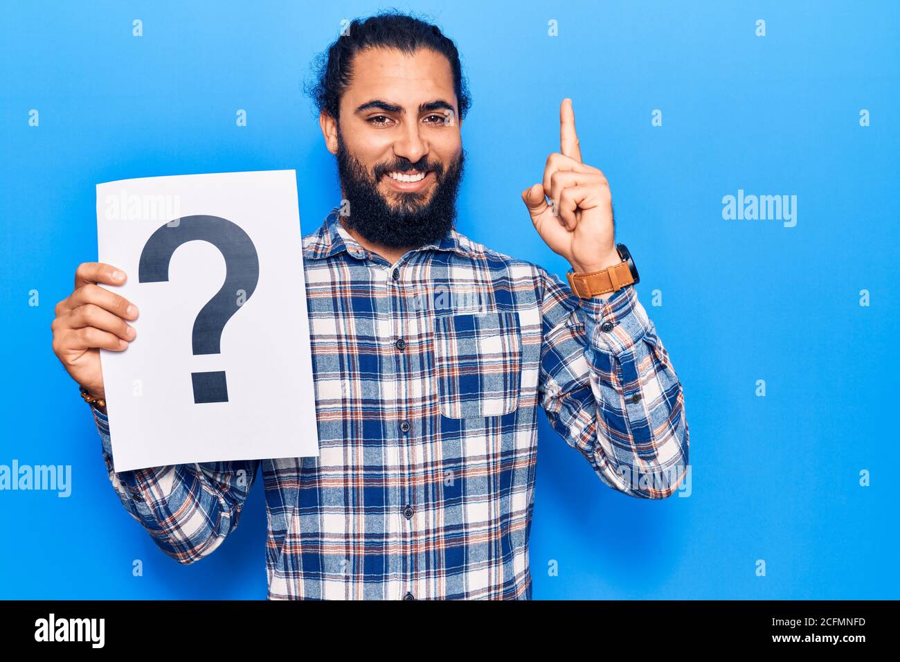 Young arab man holding question mark smiling with an idea or question ...