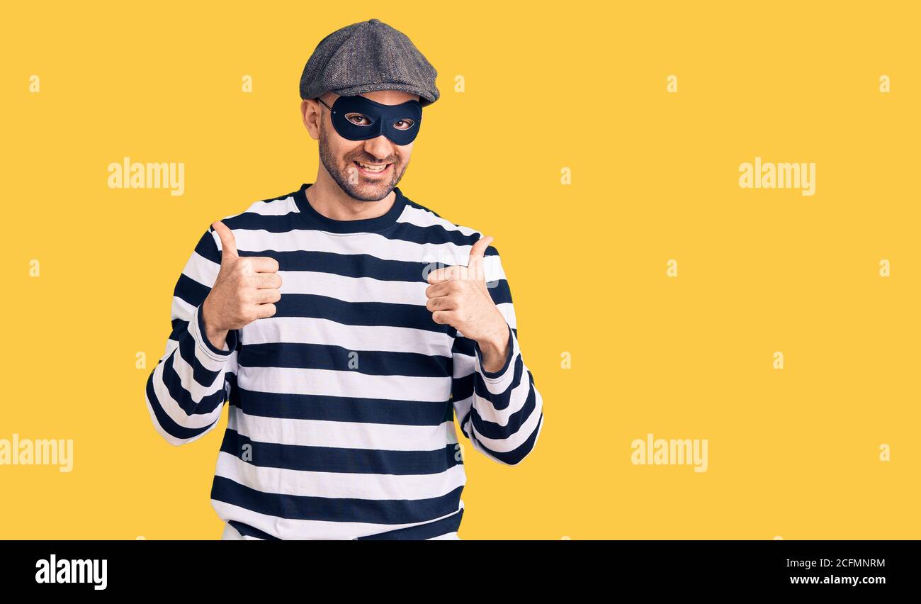 Young handsome man wearing burglar mask success sign doing positive ...