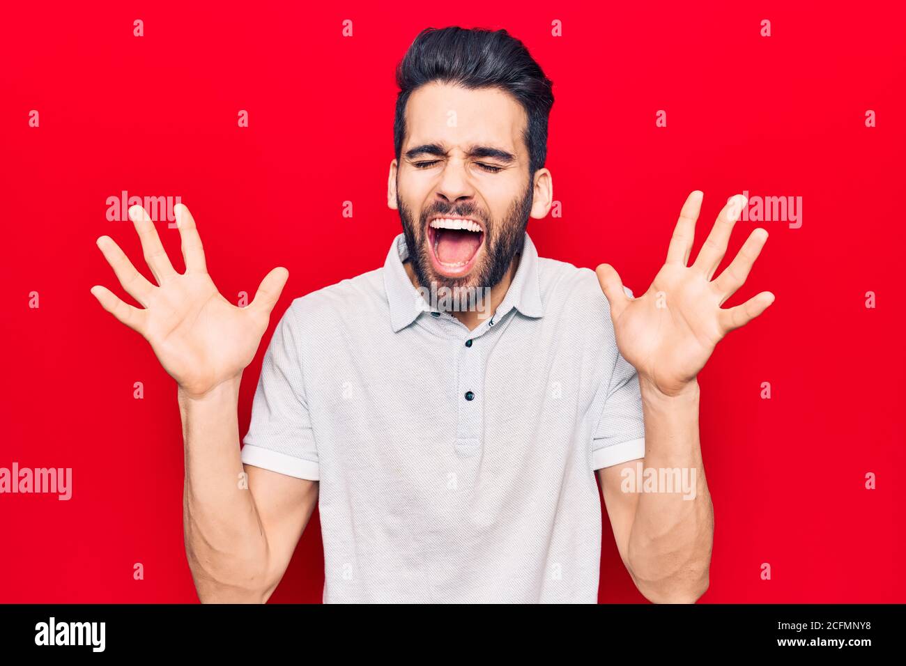 Young handsome man with beard wearing casual polo celebrating mad and ...