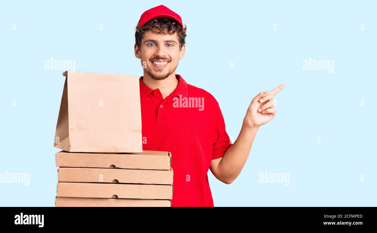 Young handsome man with curly hair holding delivery pizza box smiling ...