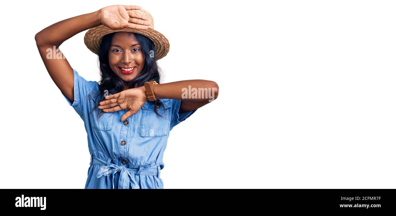 Young indian girl wearing summer hat smiling cheerful playing peek a ...