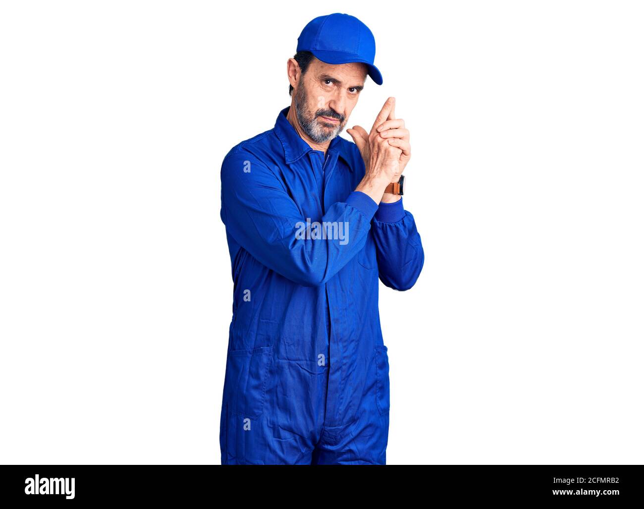 Middle age handsome man wearing mechanic uniform holding symbolic gun ...