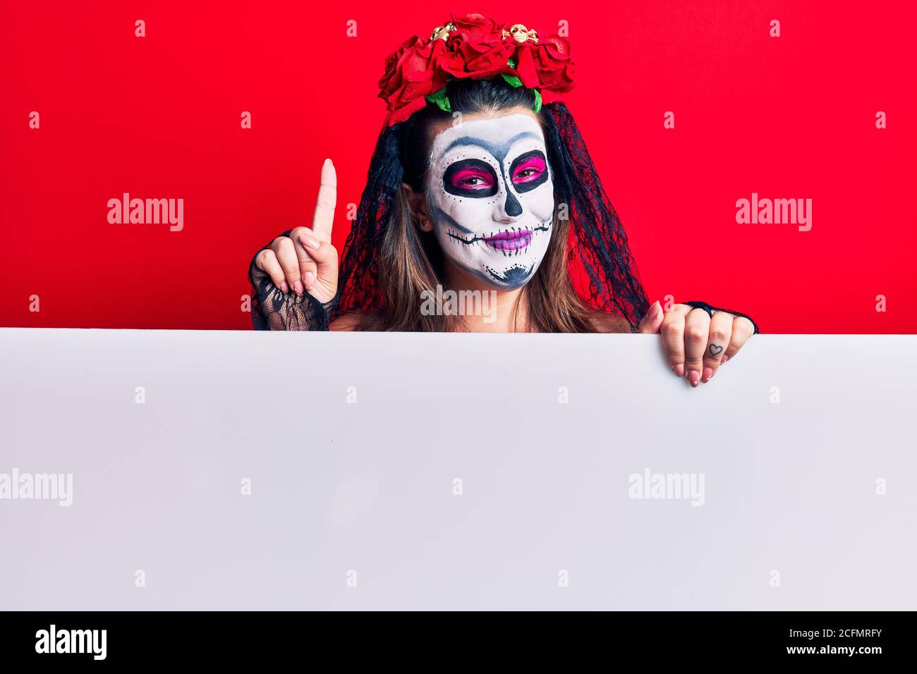 Young woman wearing day of the dead costume holding blank empty banner ...