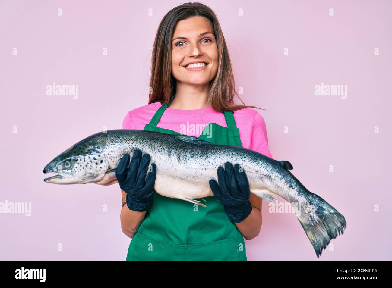 Beautiful caucasian woman fishmonger selling fresh raw salmon smiling ...