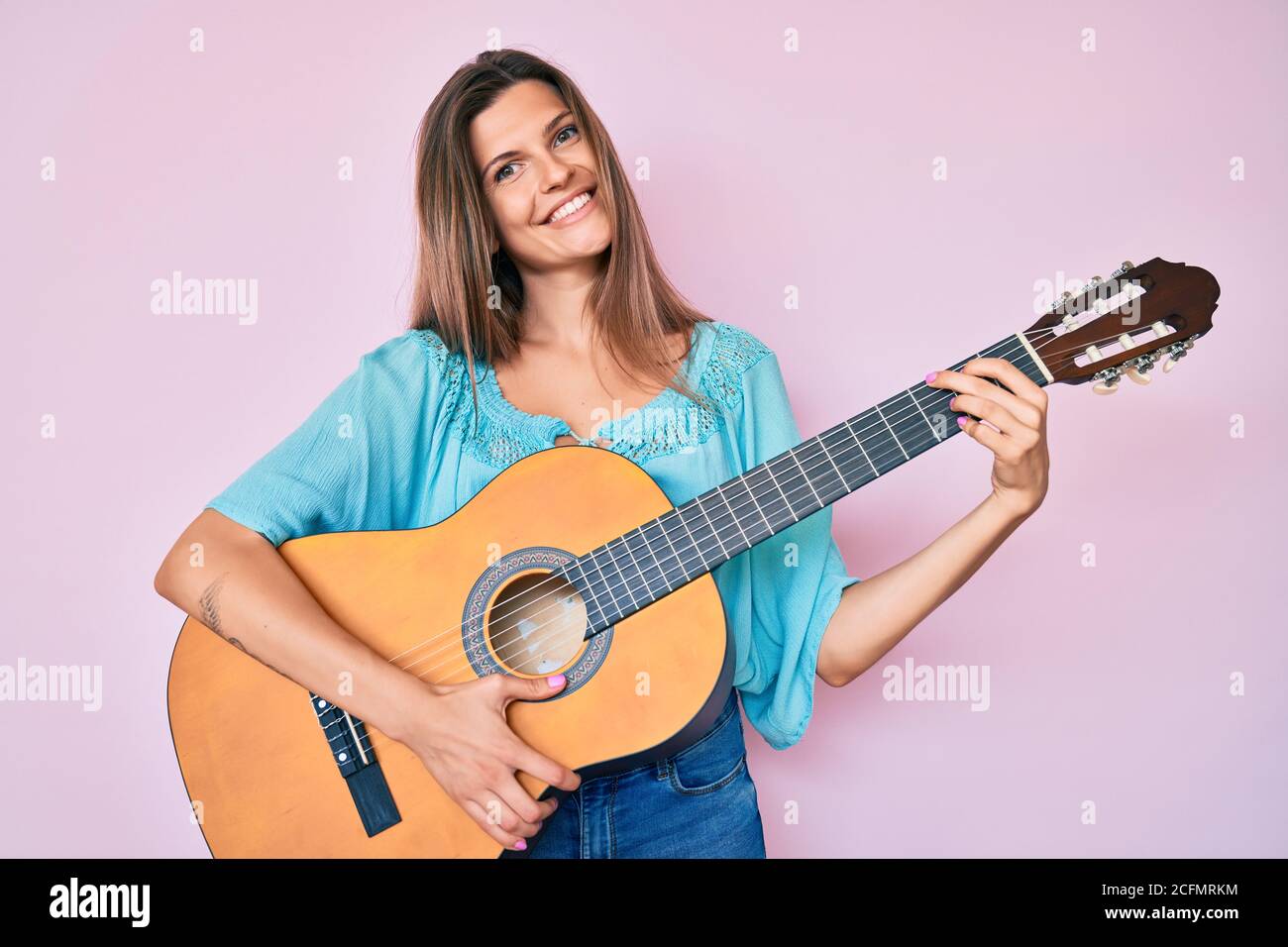 Beautiful caucasian woman playing classical guitar smiling with a happy ...