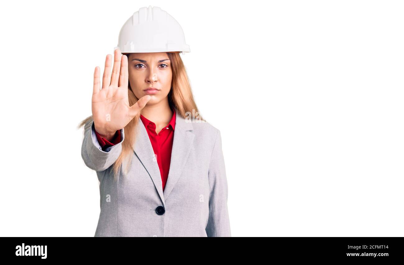 Beautiful young woman wearing architect hardhat doing stop sing with ...