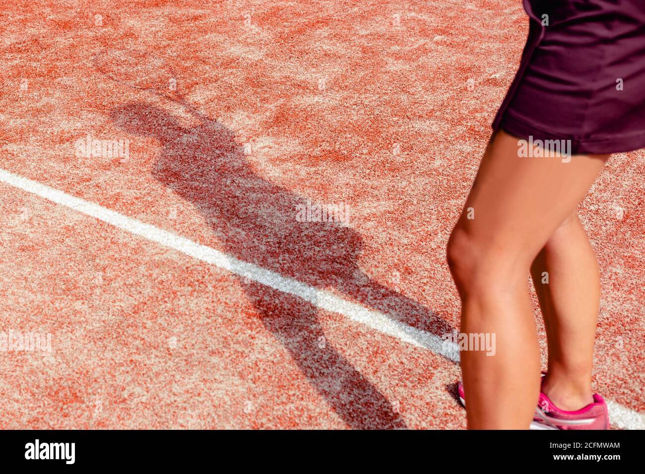 Tennis Player holding racket casting shadow on the hard red court Stock ...