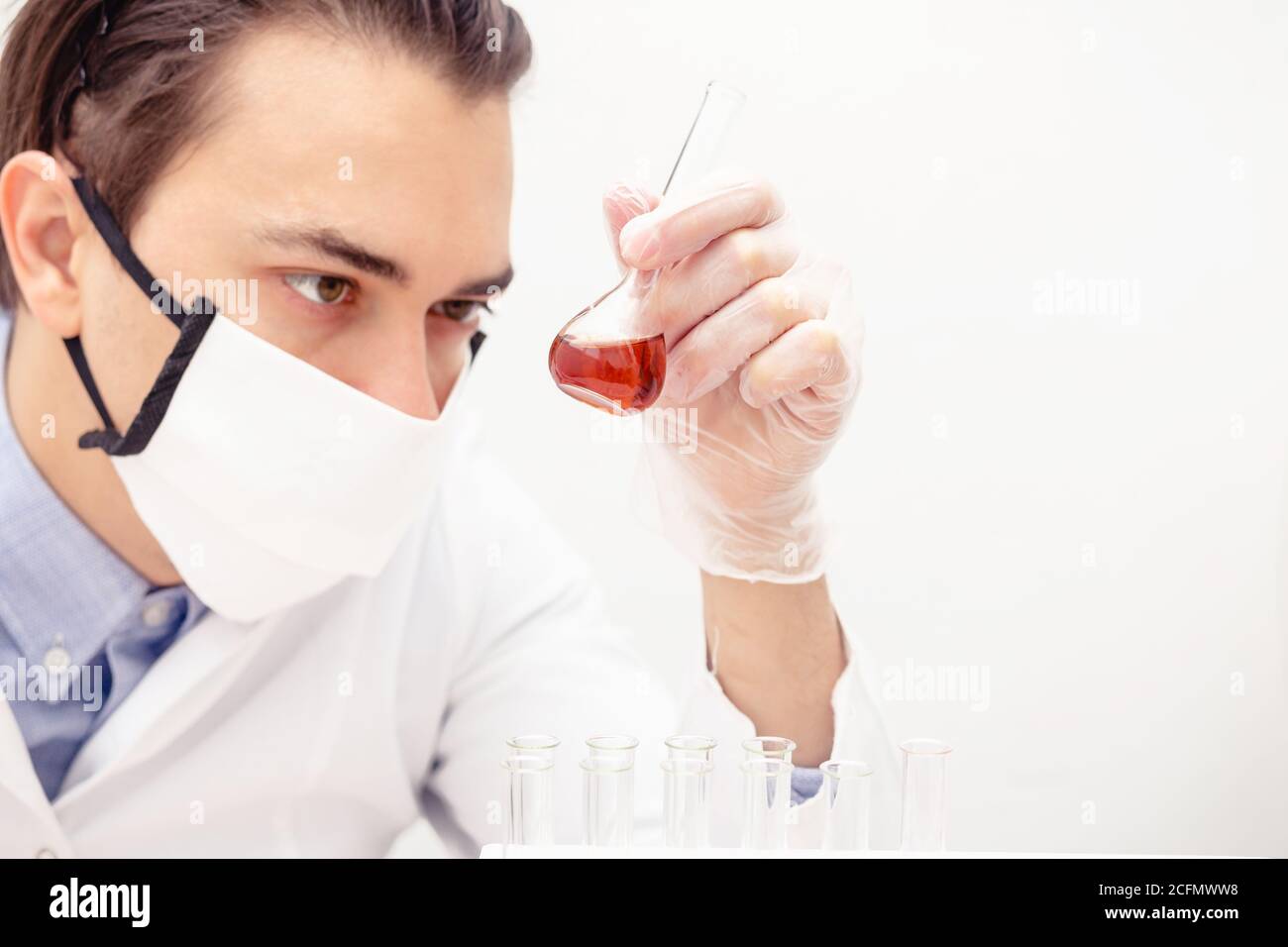 Professional scientist man looking at test-tube with interest ...
