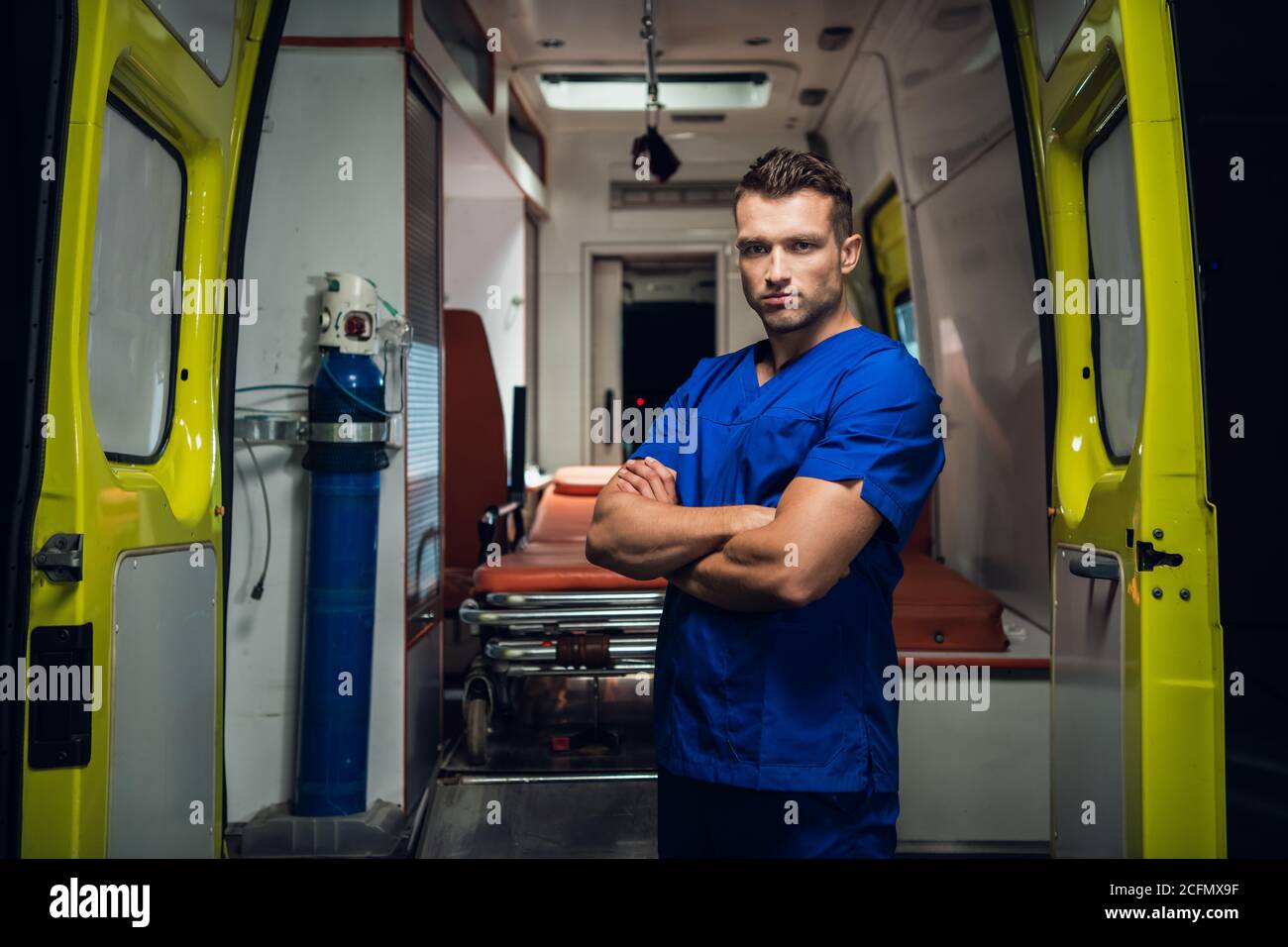 Serious corpsman looking at the camera, hands folded, ambulance car in ...