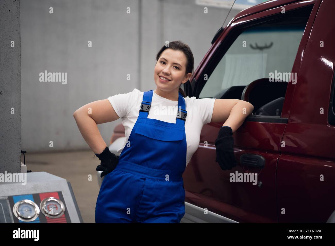 A female techie in blue overalls is standing at the car Stock Photo - Alamy
