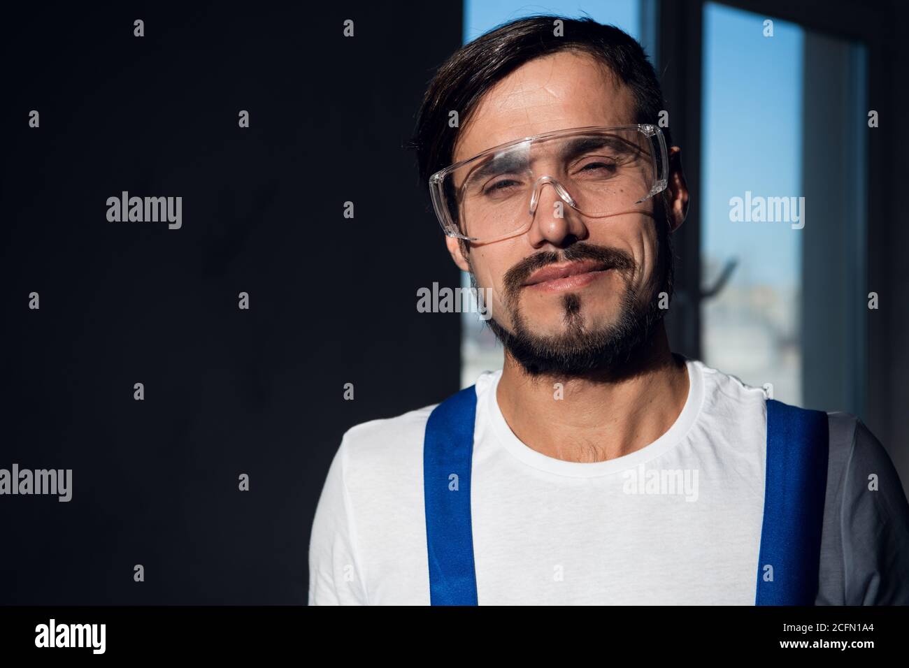 Male engineer wearing blue overalls and goggles on his head Stock Photo ...