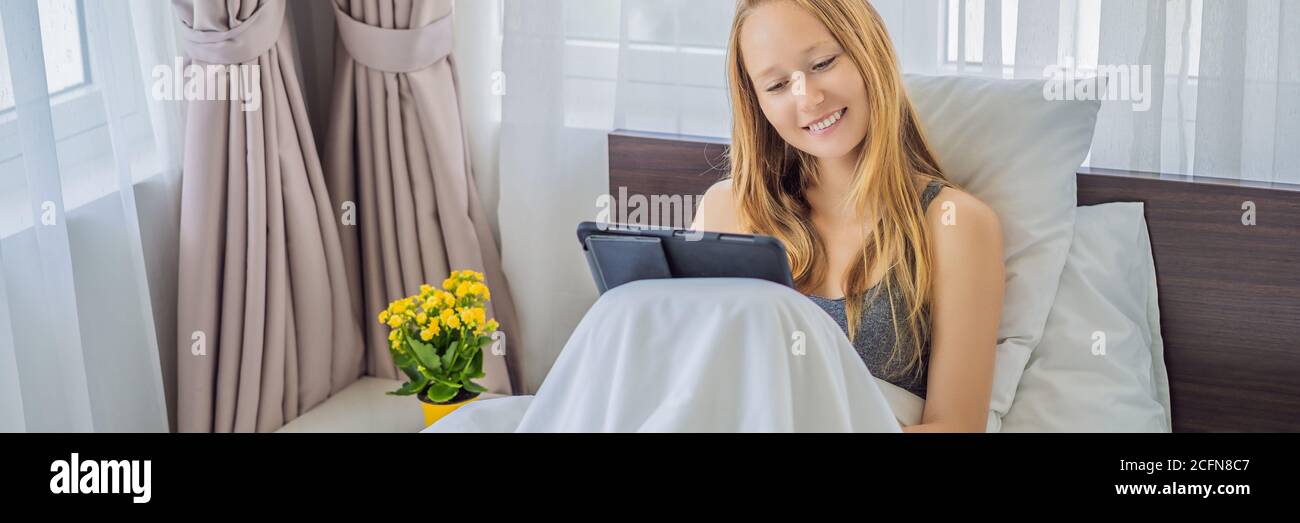 Woman talking by video call while lying in bed BANNER, LONG FORMAT ...
