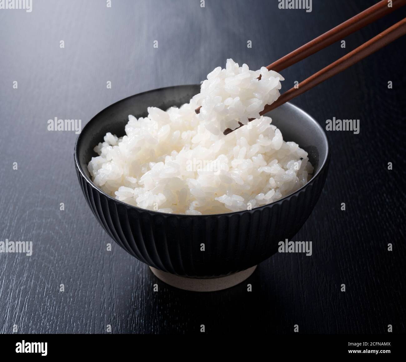 scooping rice with chopsticks on the black background Stock Photo - Alamy