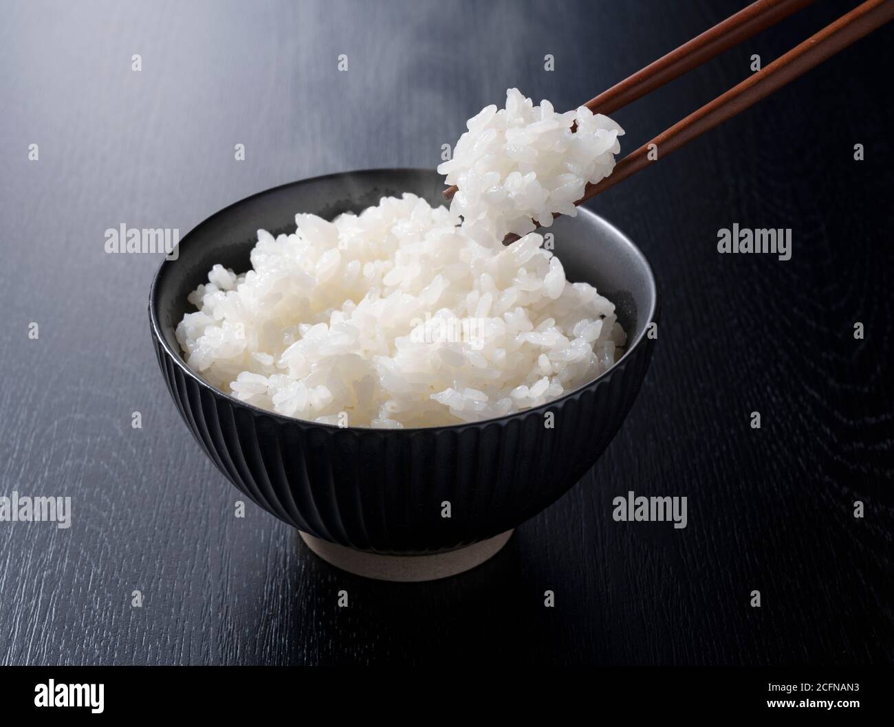 scooping rice with chopsticks on the black background Stock Photo - Alamy