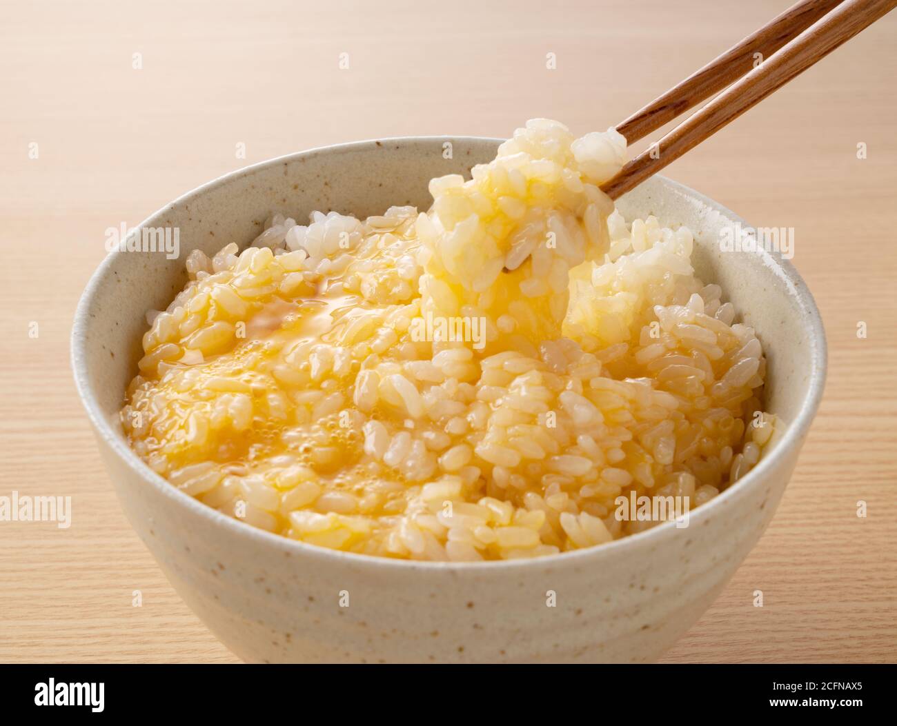 Scooping rice with chopsticks with a Japanese egg on the wooden ...