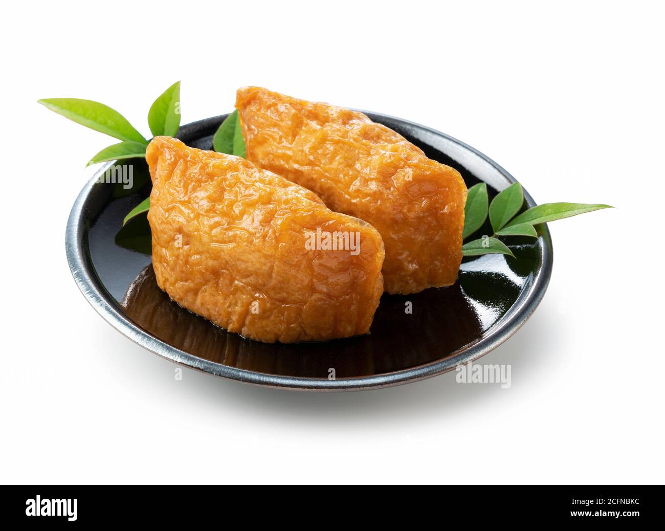 Japanese Inari Sushi on a black plate set against a white background ...