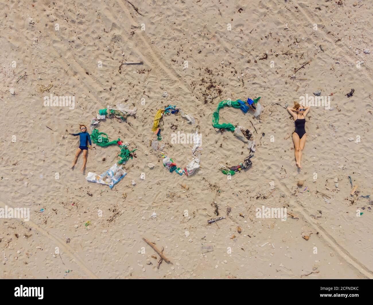 SOS lettering and mom and son sunbathe on the beach nearby ...