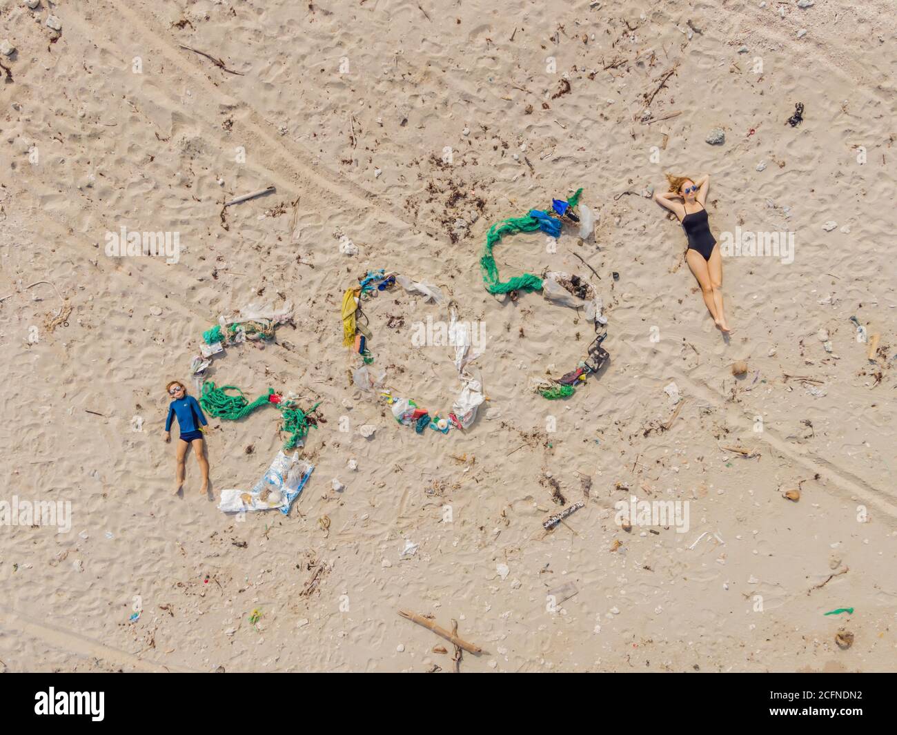 SOS lettering and mom and son sunbathe on the beach nearby ...