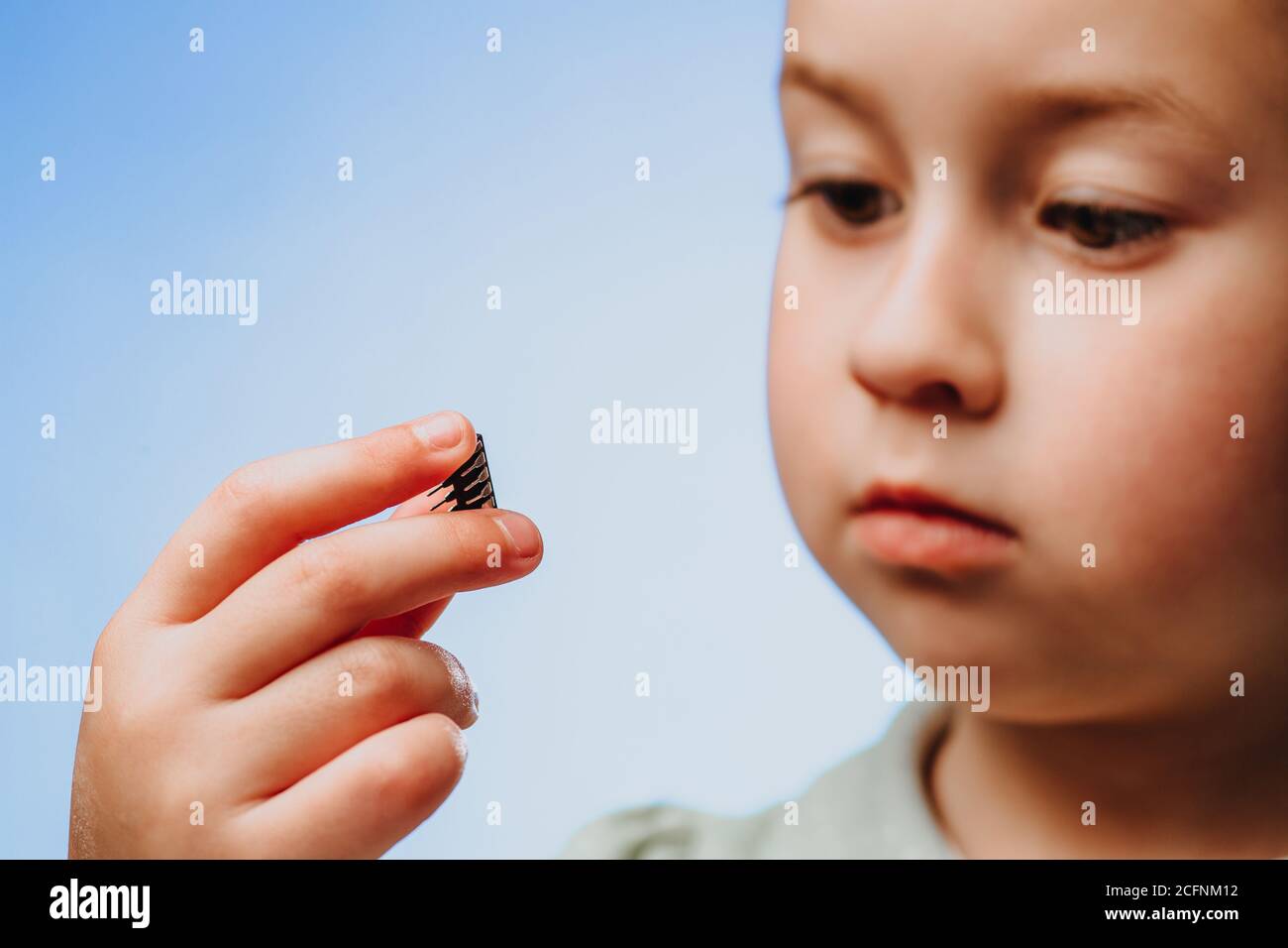 A girl holds in her hand and examines a small black chip. Chipization ...