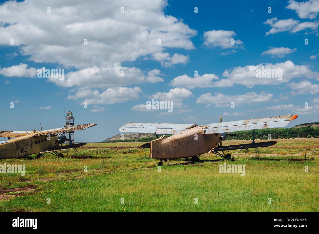 Abandoned, destroyed, rusty old planes stand on the grass under a blue ...