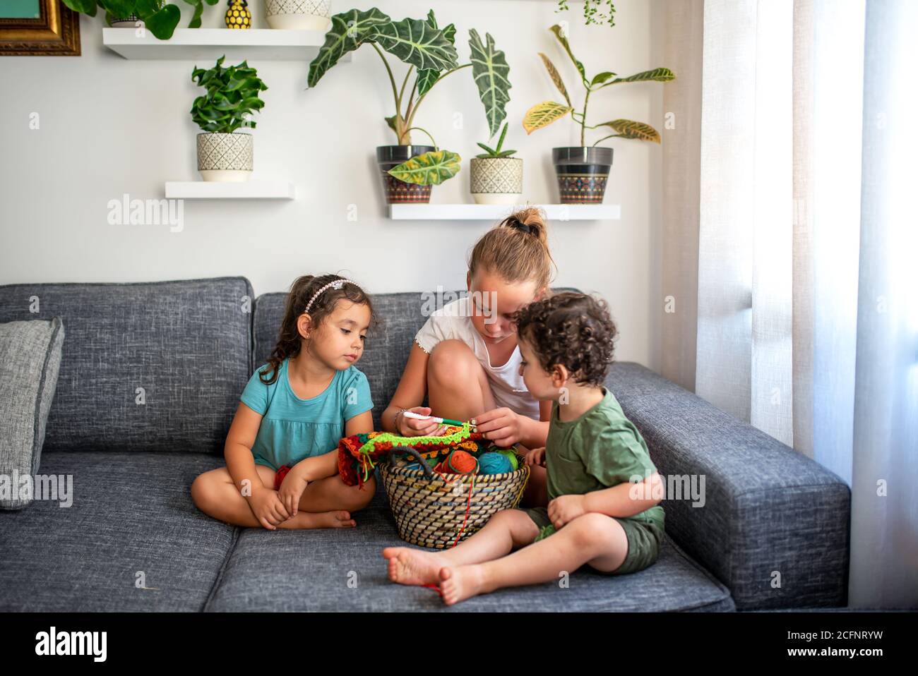 Children knitting together, sitting on couch in the home, cozy living ...