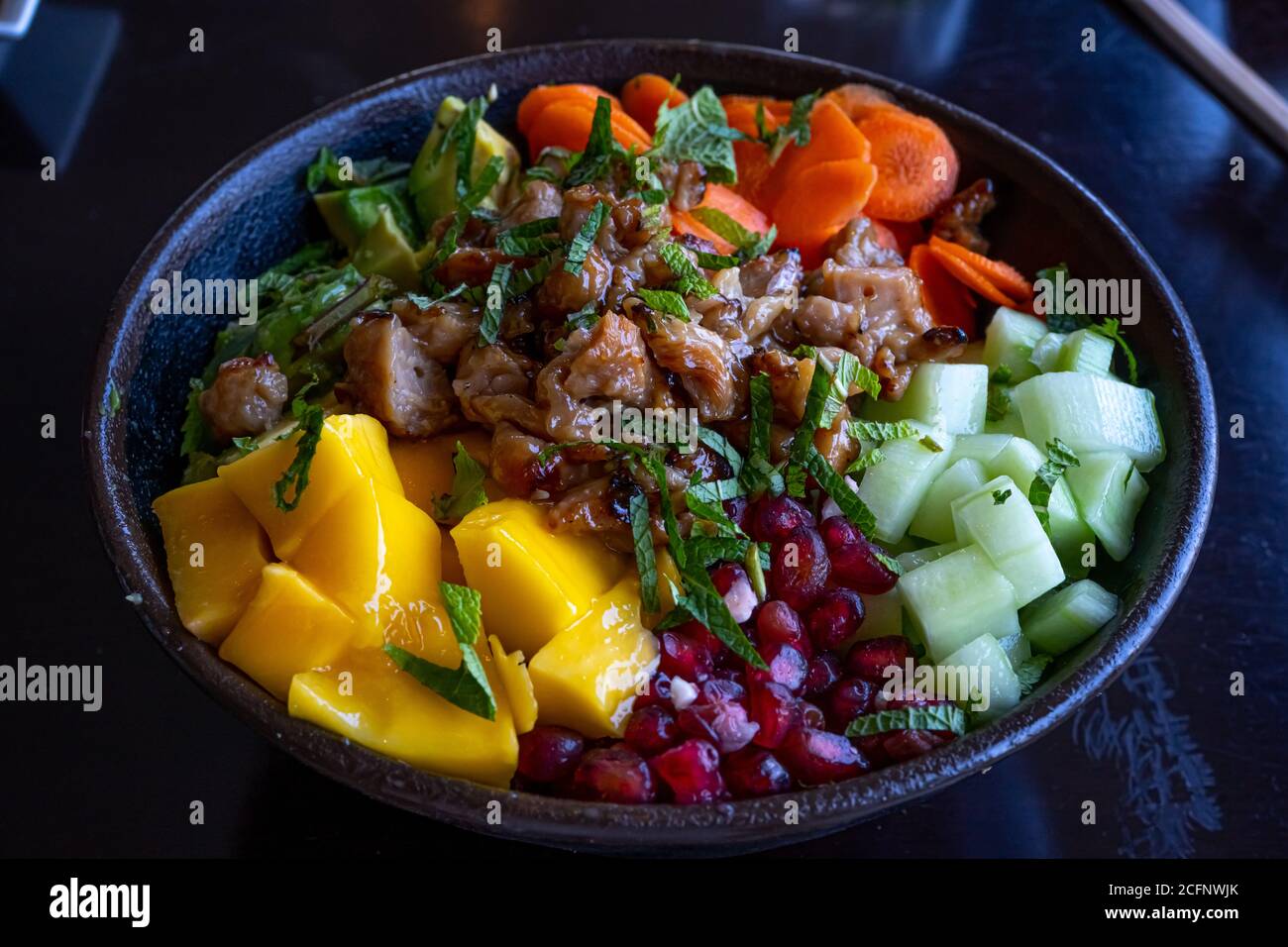Asian food concept. Poke bowl of fried rice with meat, fresh fruits and ...