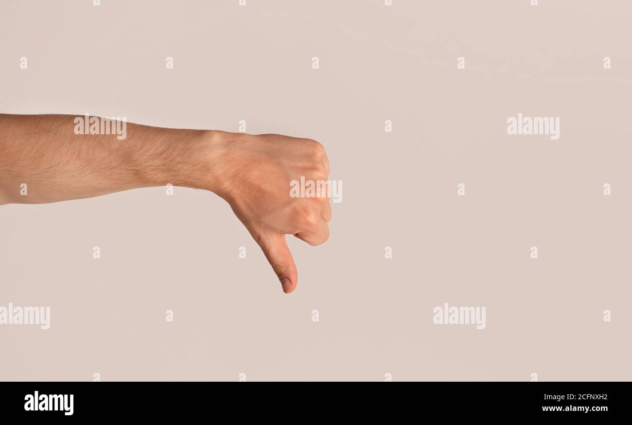 Millennial guy showing thumb down gesture, expressing negativity over ...