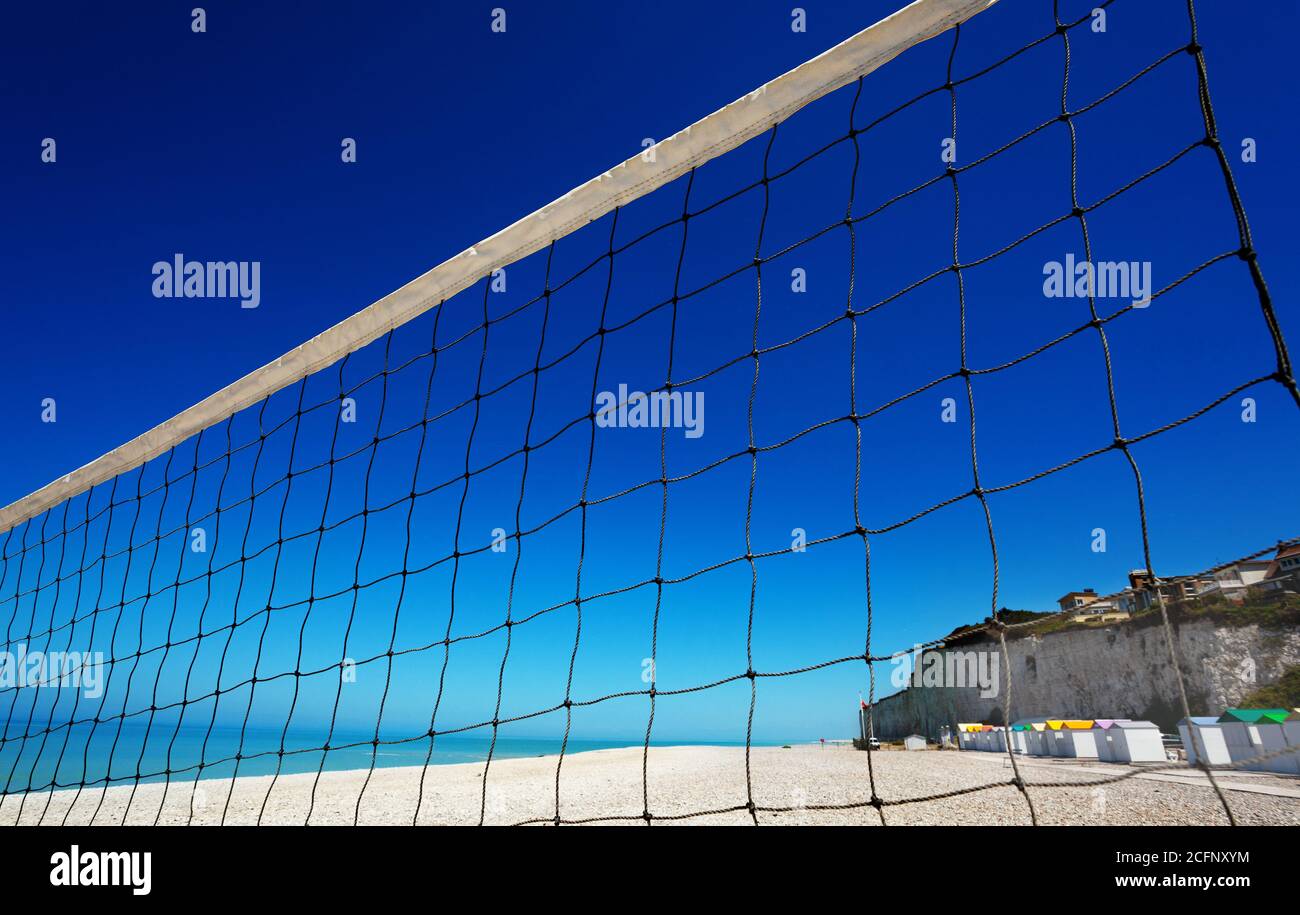 Close-up view of a volleyball net over clean sand beach and ocean ...
