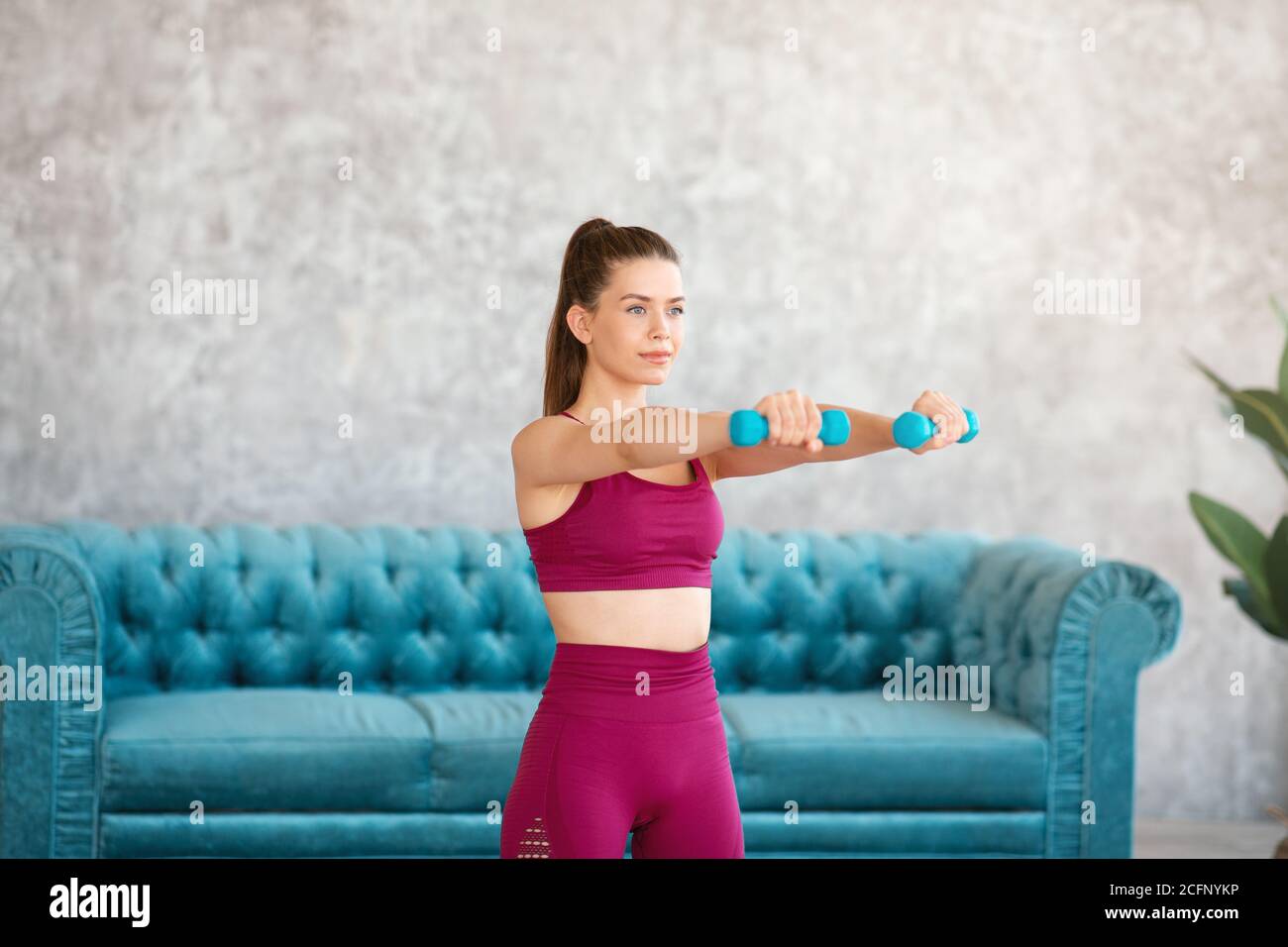 Home training. Strong young woman doing exercises with dumbbells at ...