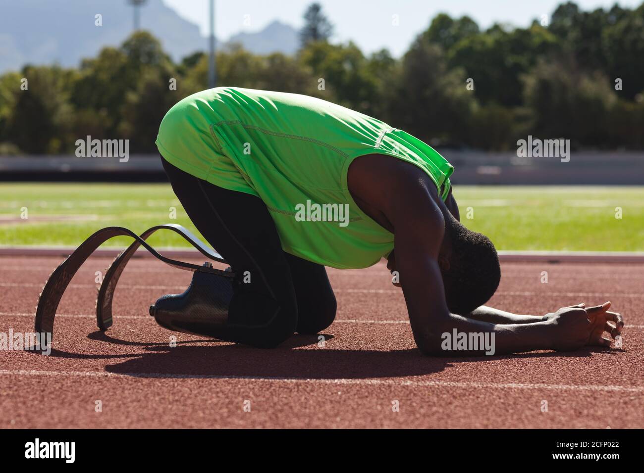 Male athlete with prosthetic leg kneeling on race track Stock Photo - Alamy