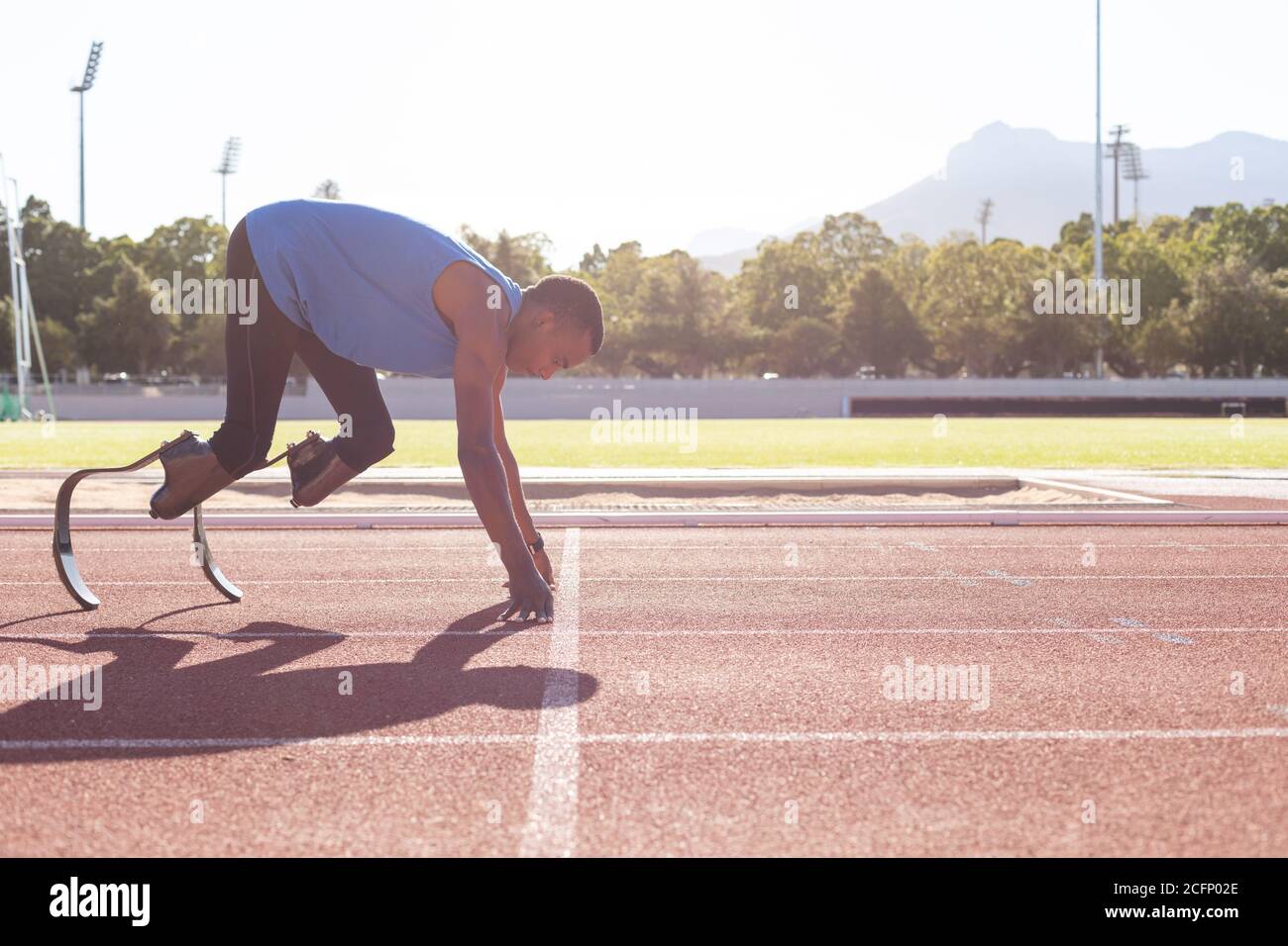 Male athlete with prosthetic leg bending on race track before the race ...
