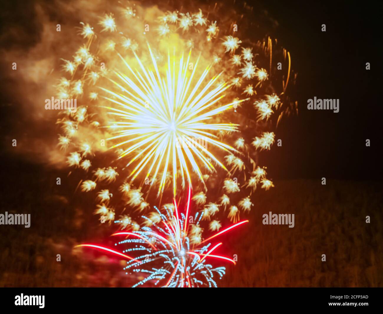 Two bright blurry flashes of fireworks in golden and blue color with ...