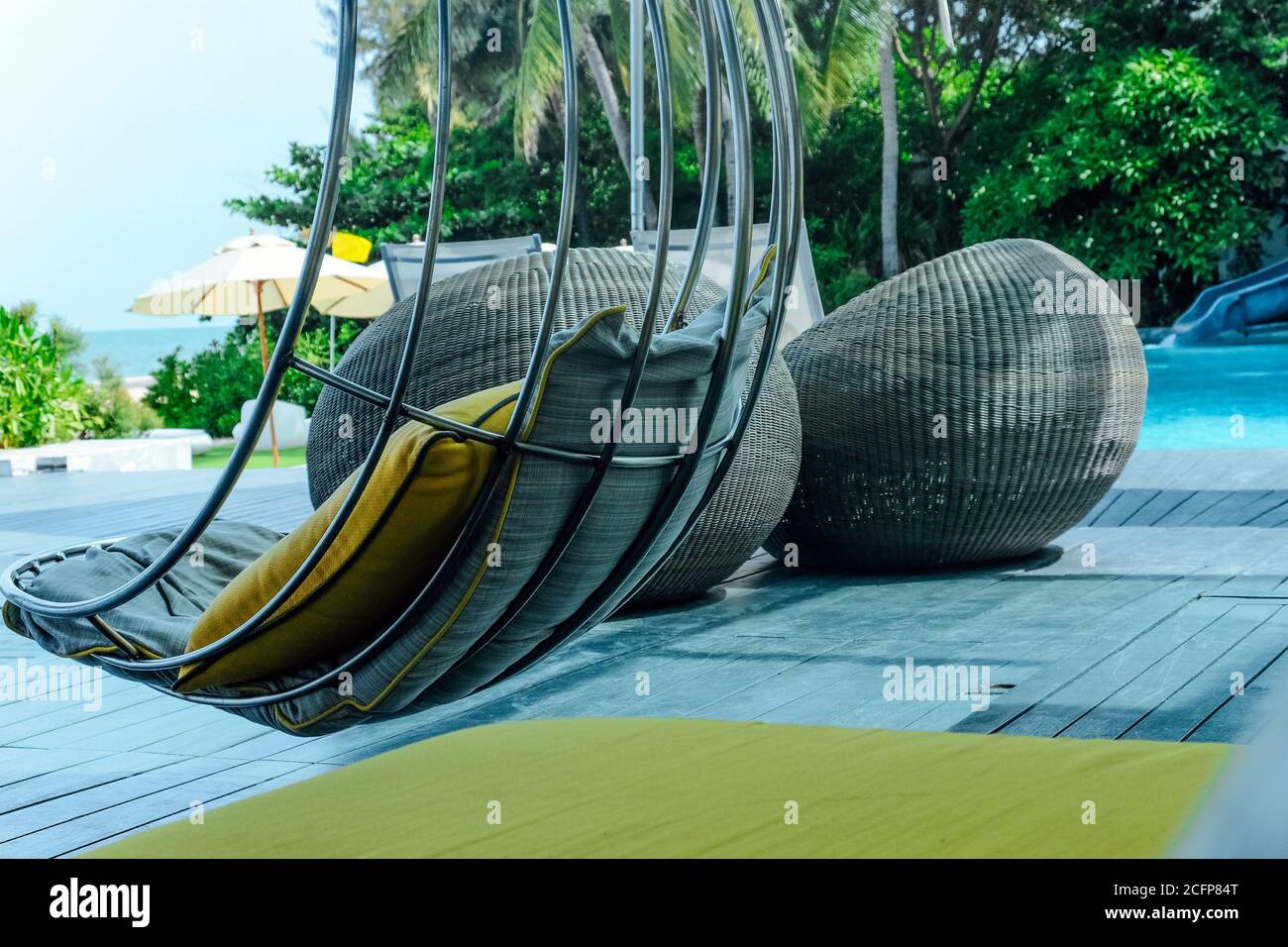 Image of Relaxing chairs with pillows beside swimming pool Stock Photo ...