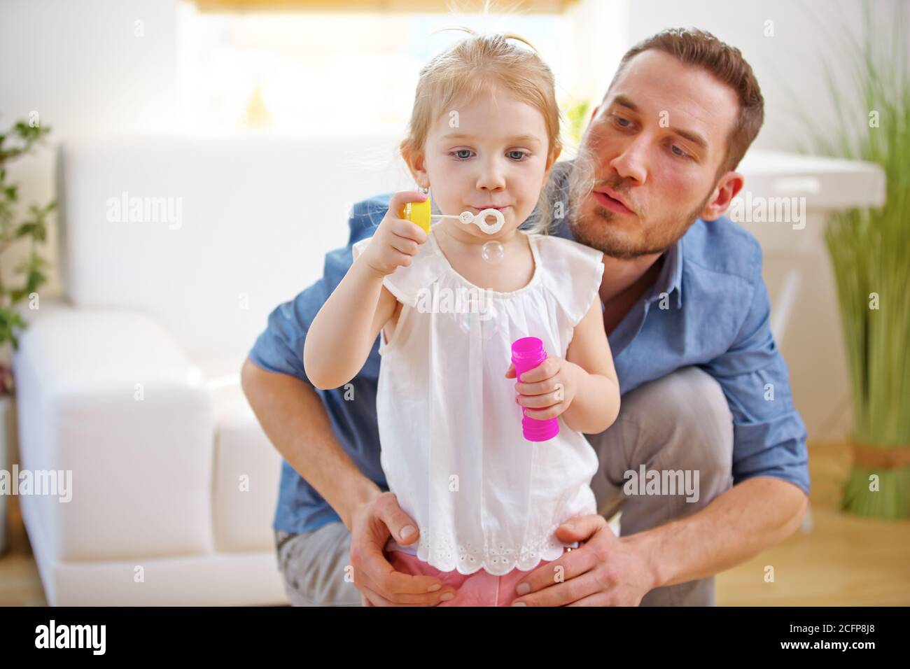 Father and daughter making soap bubbles at home Stock Photo - Alamy