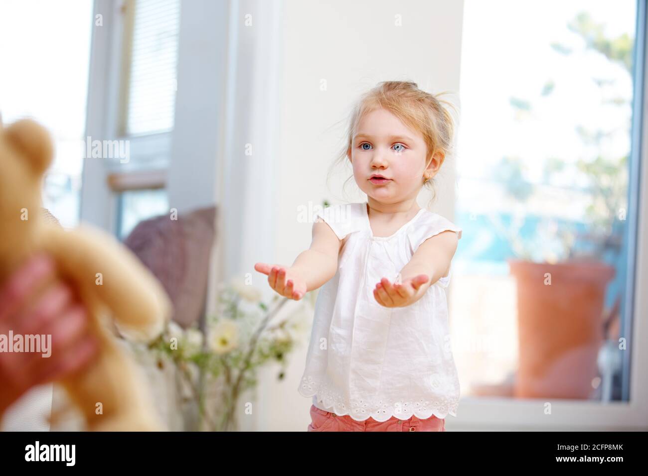 Girl wants to catch teddy bear with both hands Stock Photo - Alamy